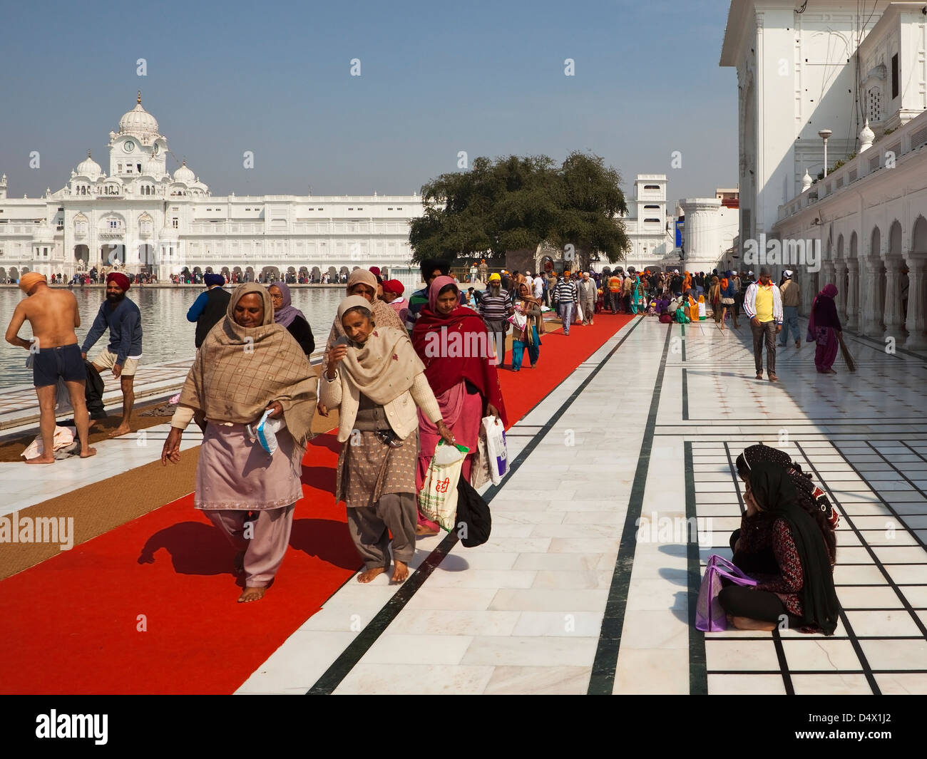 Pilgrims walking around the Holy Pool inside the Golden Temple complex ...