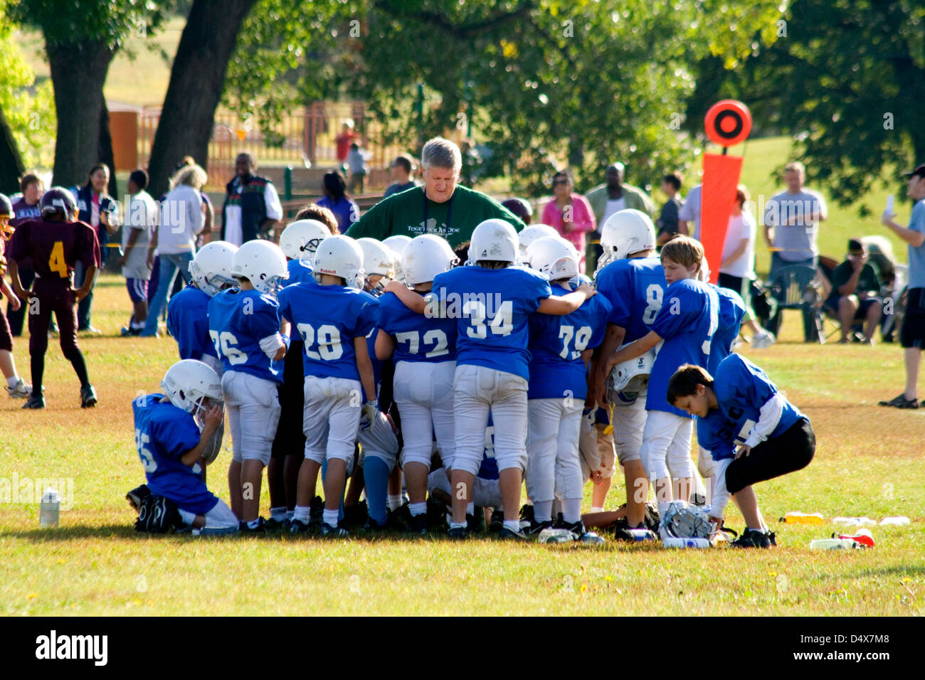 Young football players age 10 huddling around coach listening to his ...