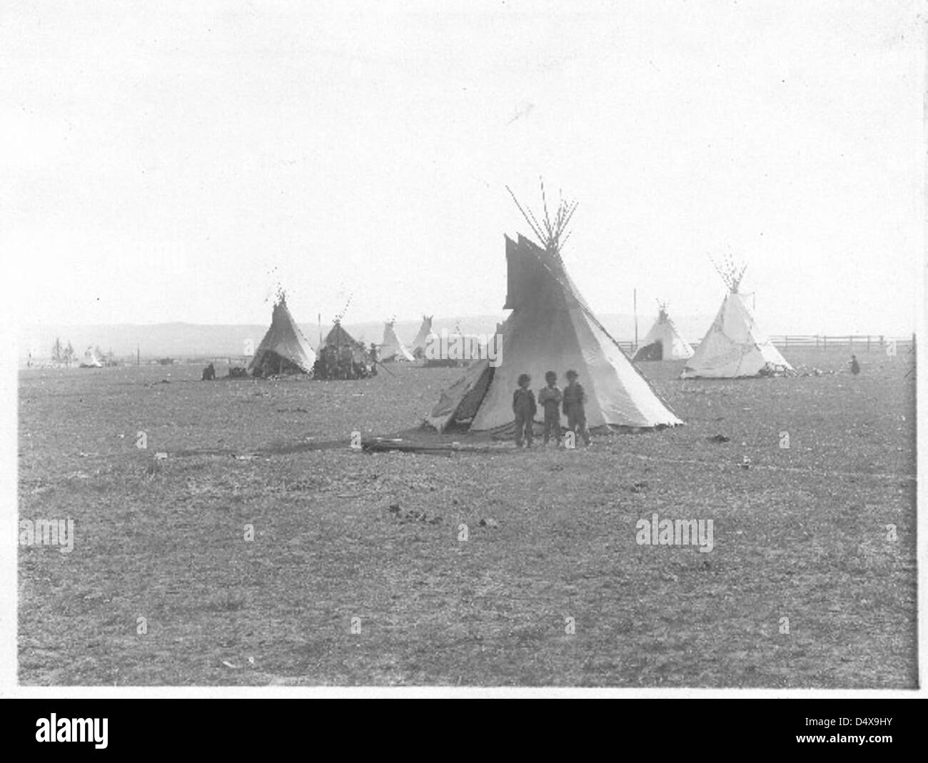 Three children stand in front of a tipi at the Flathead Irrigation ...