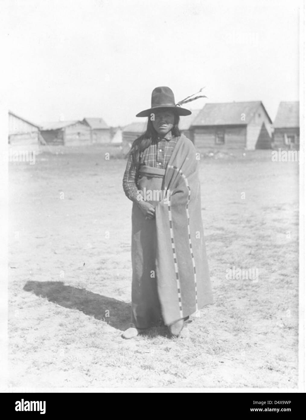 This image shows a Native American boy wrapped in a blanket standing in ...