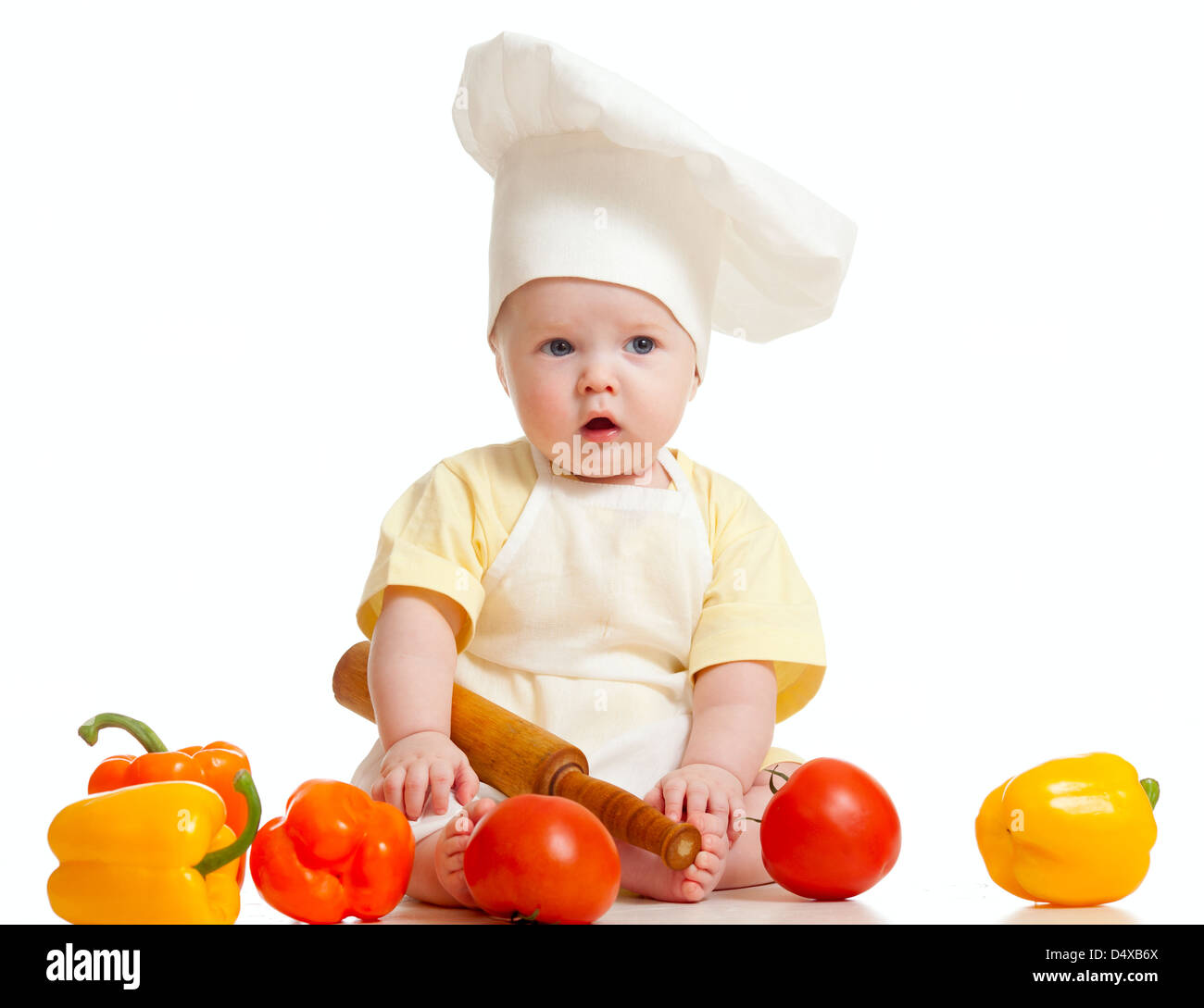 Portrait of a baby wearing a chef hat with healthy food vegetables ...
