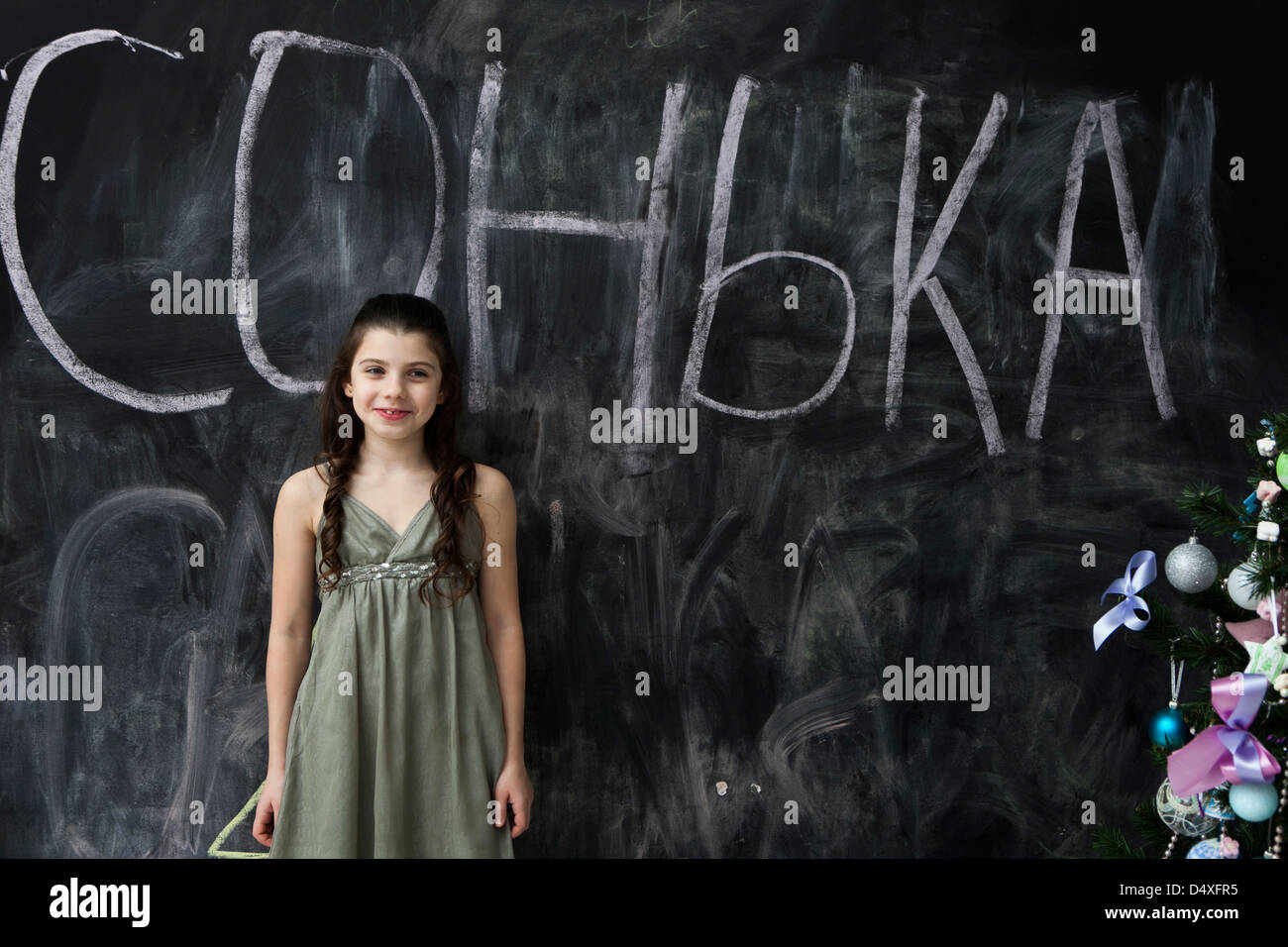 young girl smiling at blackboard with chalk. Study russian language ...