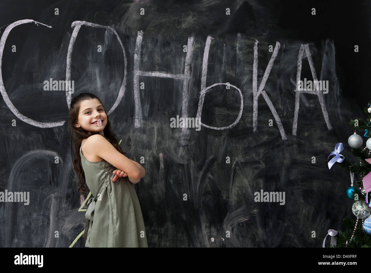 young girl smiling at blackboard with chalk. Study russian language ...