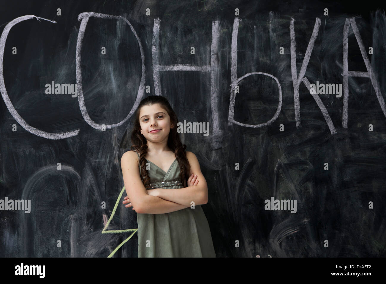 young girl smiling at blackboard with chalk. Study russian language ...