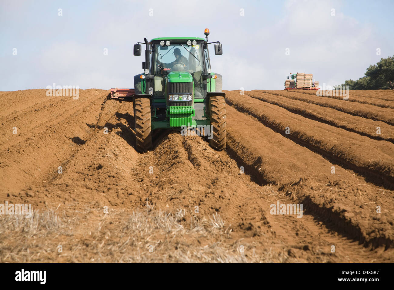 Farm machinery preparing and planting a crop of potatoes in a field ...