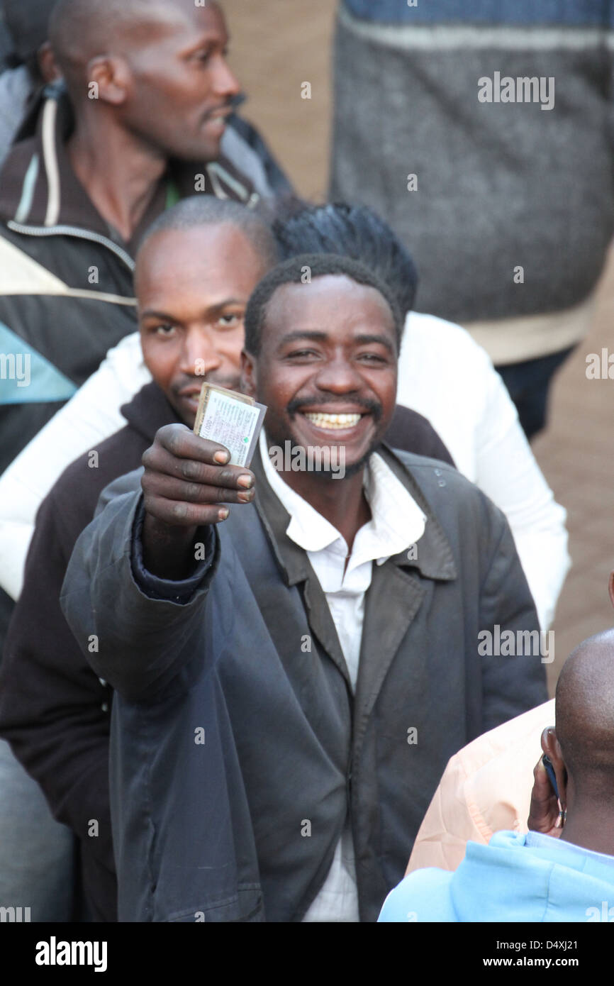 A Westlands resident shows off his ID and voters card at New Kihumbuini ...