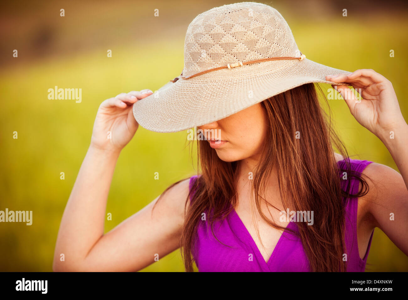 Young girl on field hiding behind her hat Stock Photo - Alamy