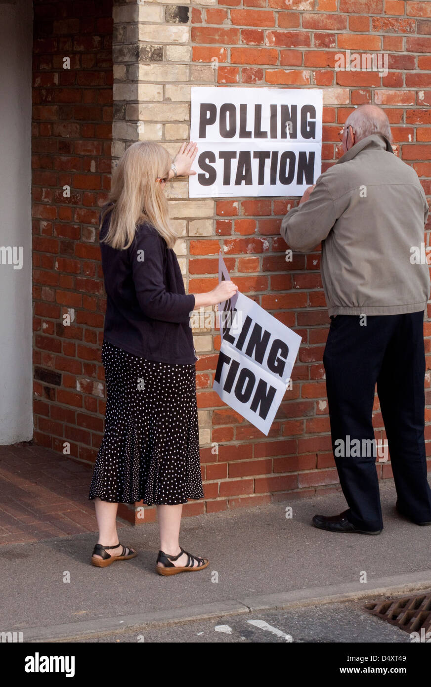 Two polling station clerks put up a notice Stock Photo - Alamy
