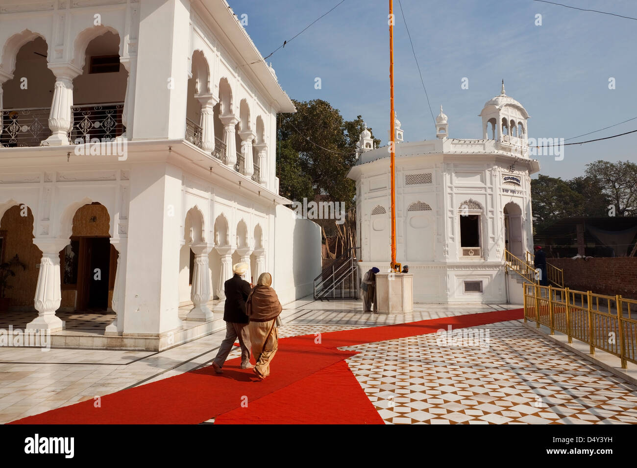 A Sikh couple walking along a red carpet inside the Golden Temple ...