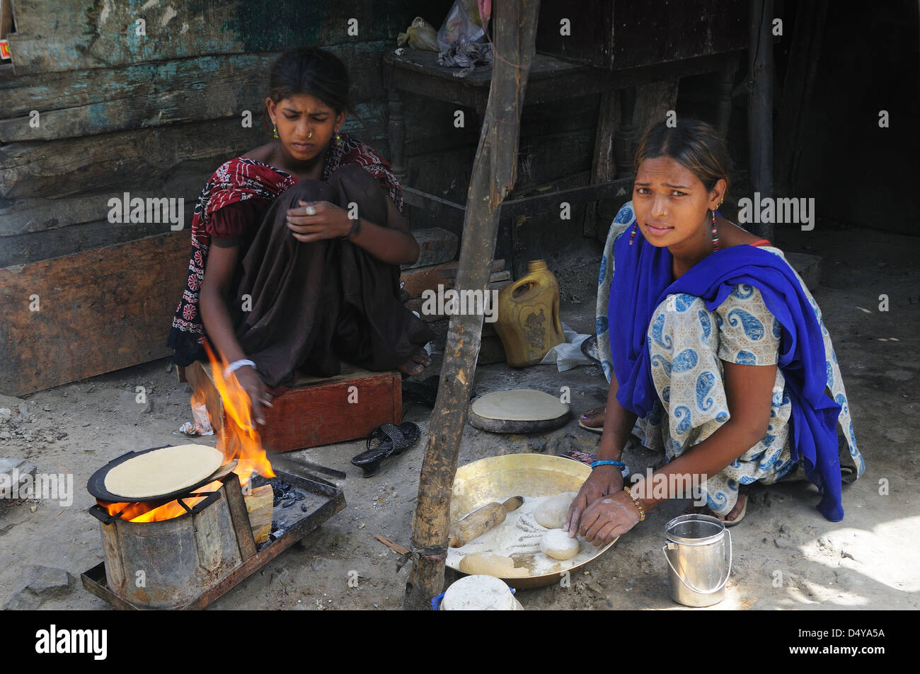 Katputli colony slum. Girls cooking in front of the house by the street ...