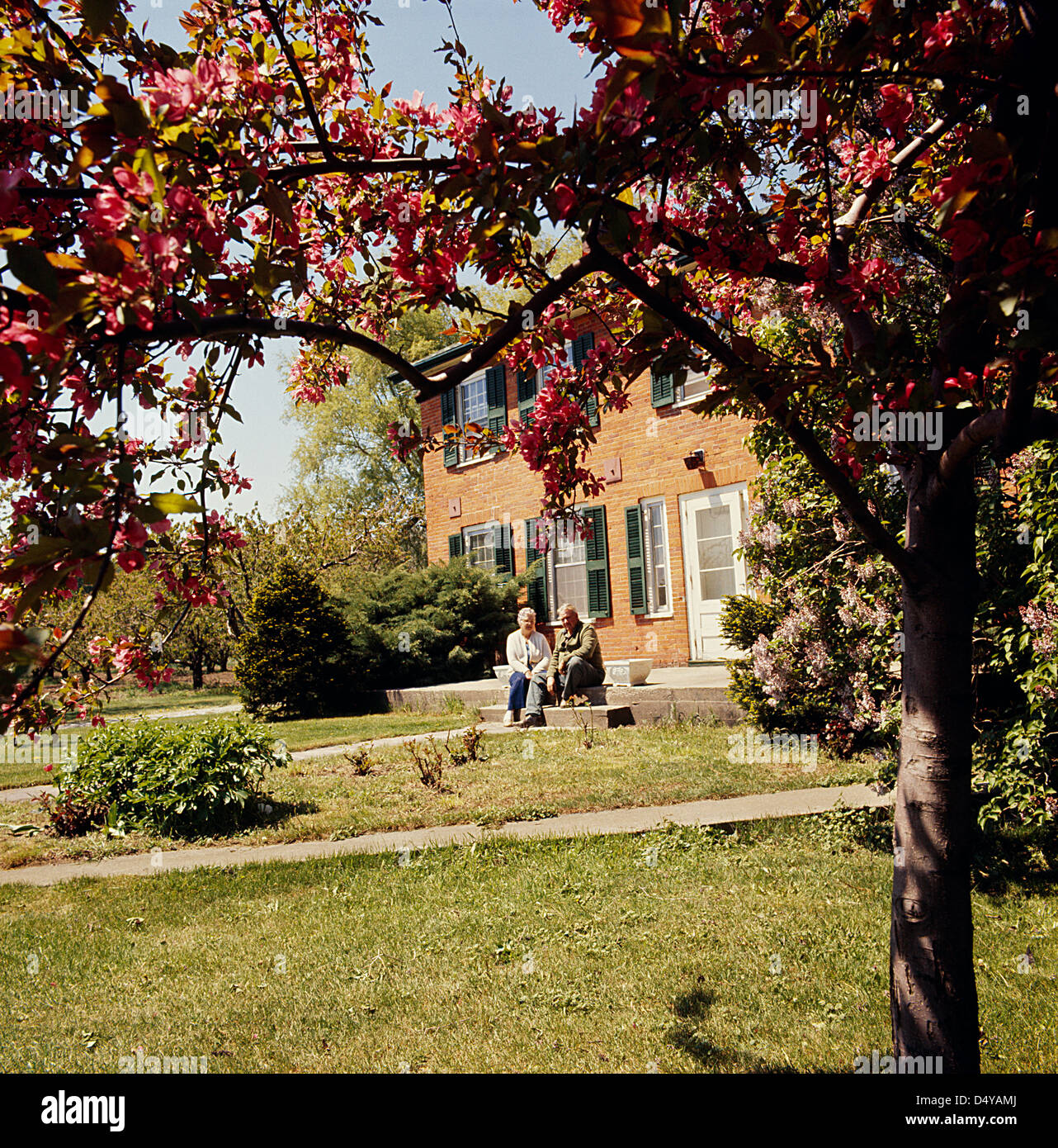 A couple or two older people sitting in front of their farm house in ...