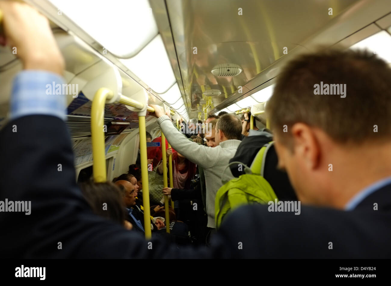 A busy Tube carriage in London full of people standing and sitting ...