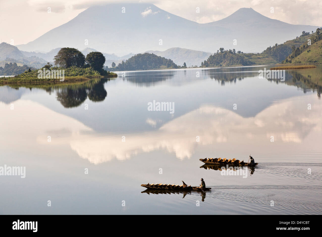 Dugout canoe floating on Lake Mutanda with the Virunga Volcanoes in the ...