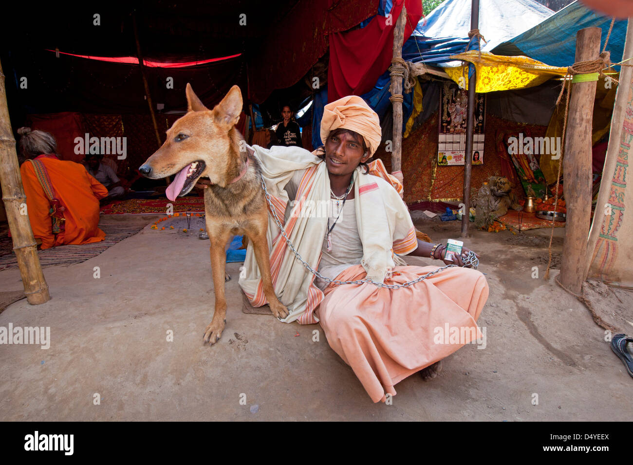 Hindu sadhus sit with their dogs at their tents during the Kumbh Mela ...