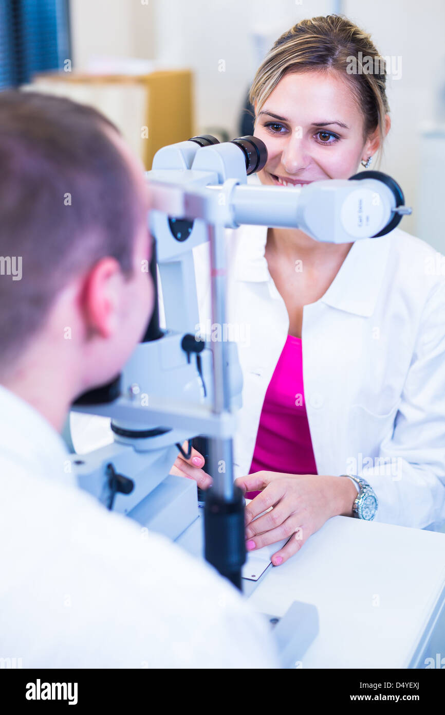 Optometry concept - handsome young man having his eyes examined by an ...