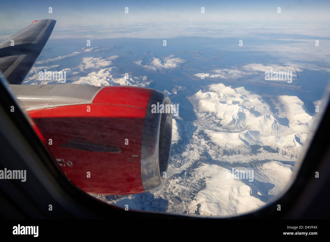 looking out of aircraft window over snow covered fjords and coastline ...