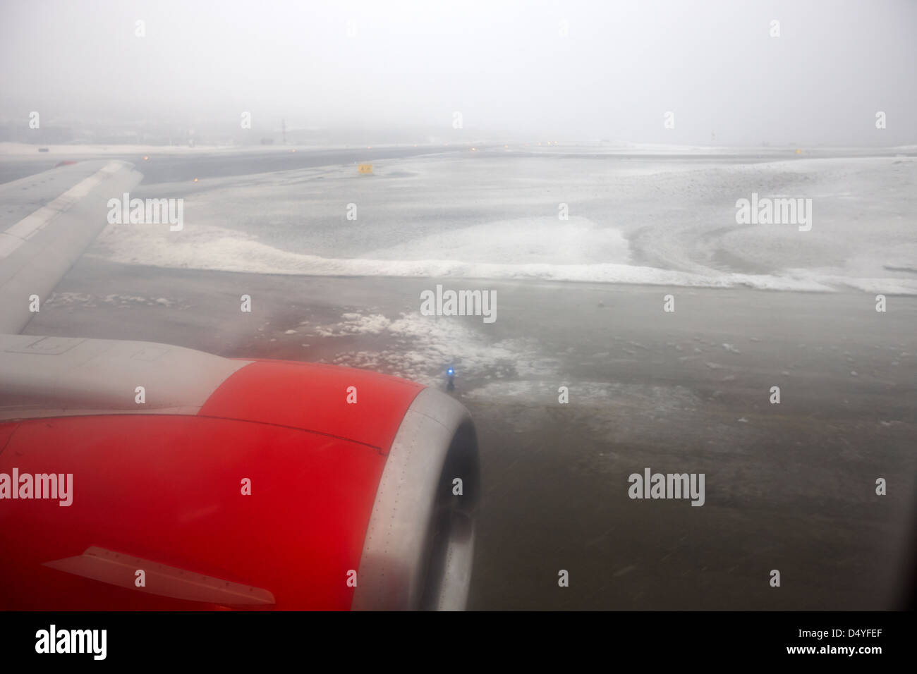 looking out of aircraft window over snow covered foggy airport runway ...