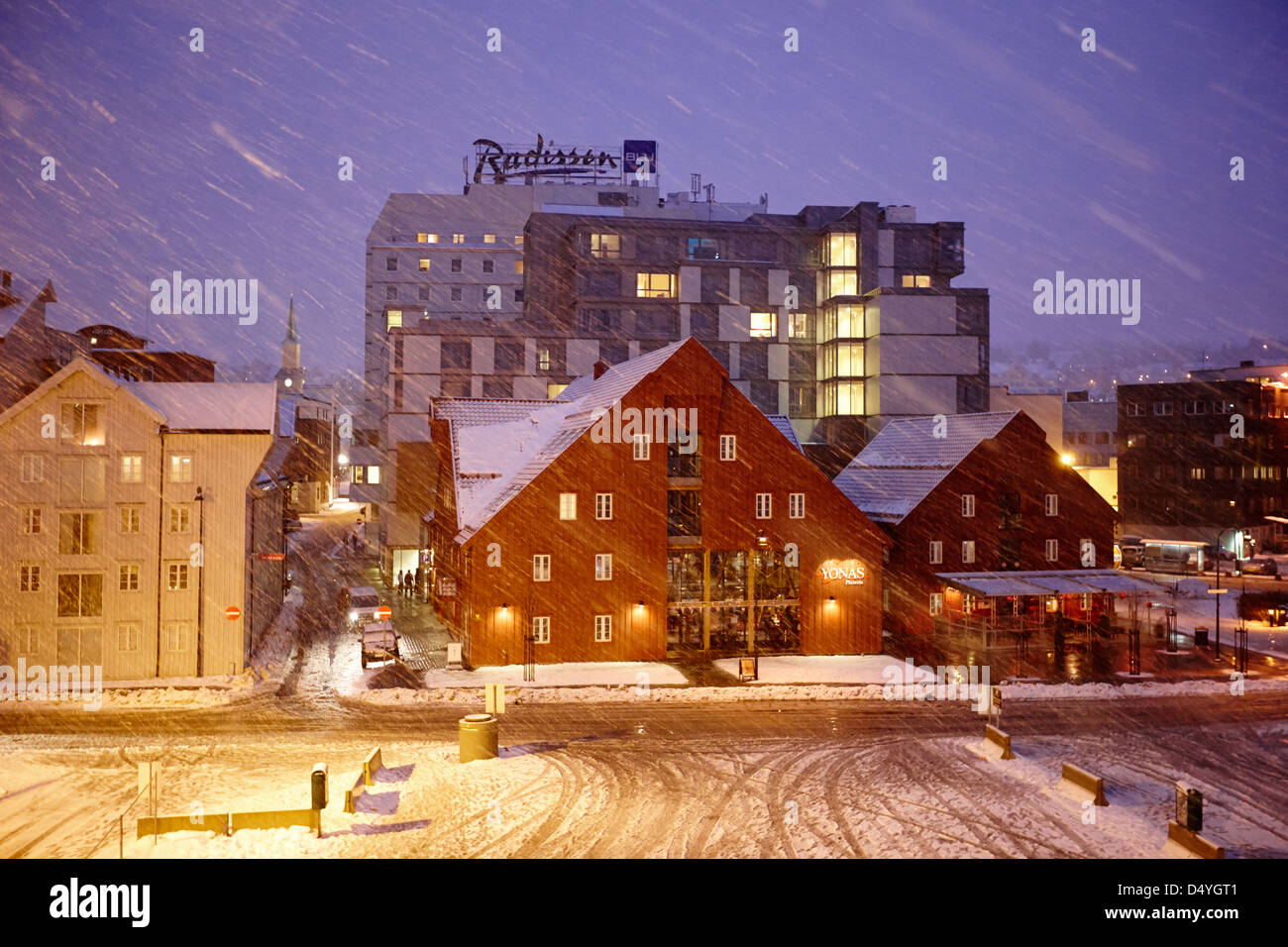 looking out at Tromso bryggen quay harbour on a cold snowy winter night ...