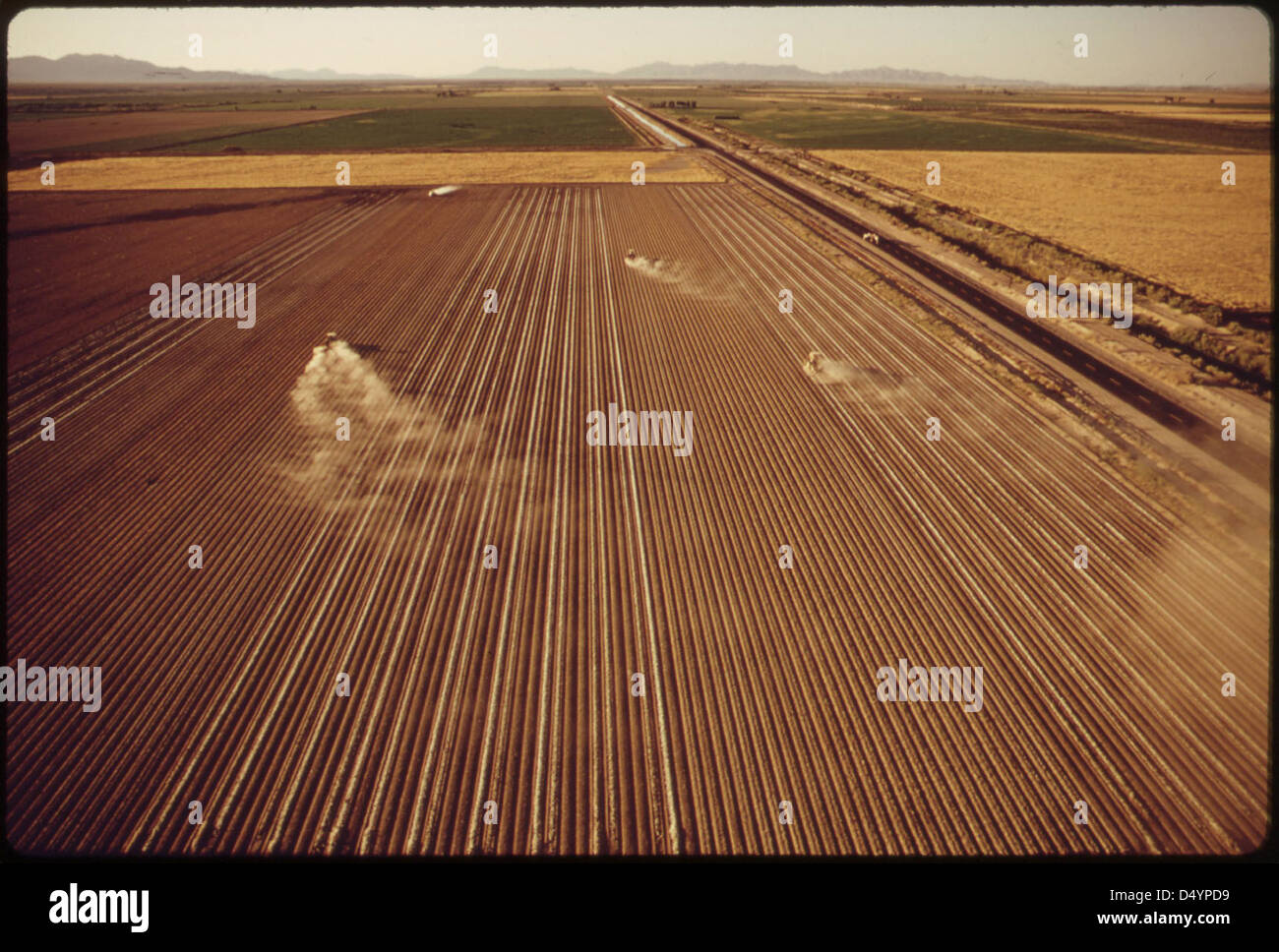 A 1972 photograph shows the process of fertilizing a field, part of the ...