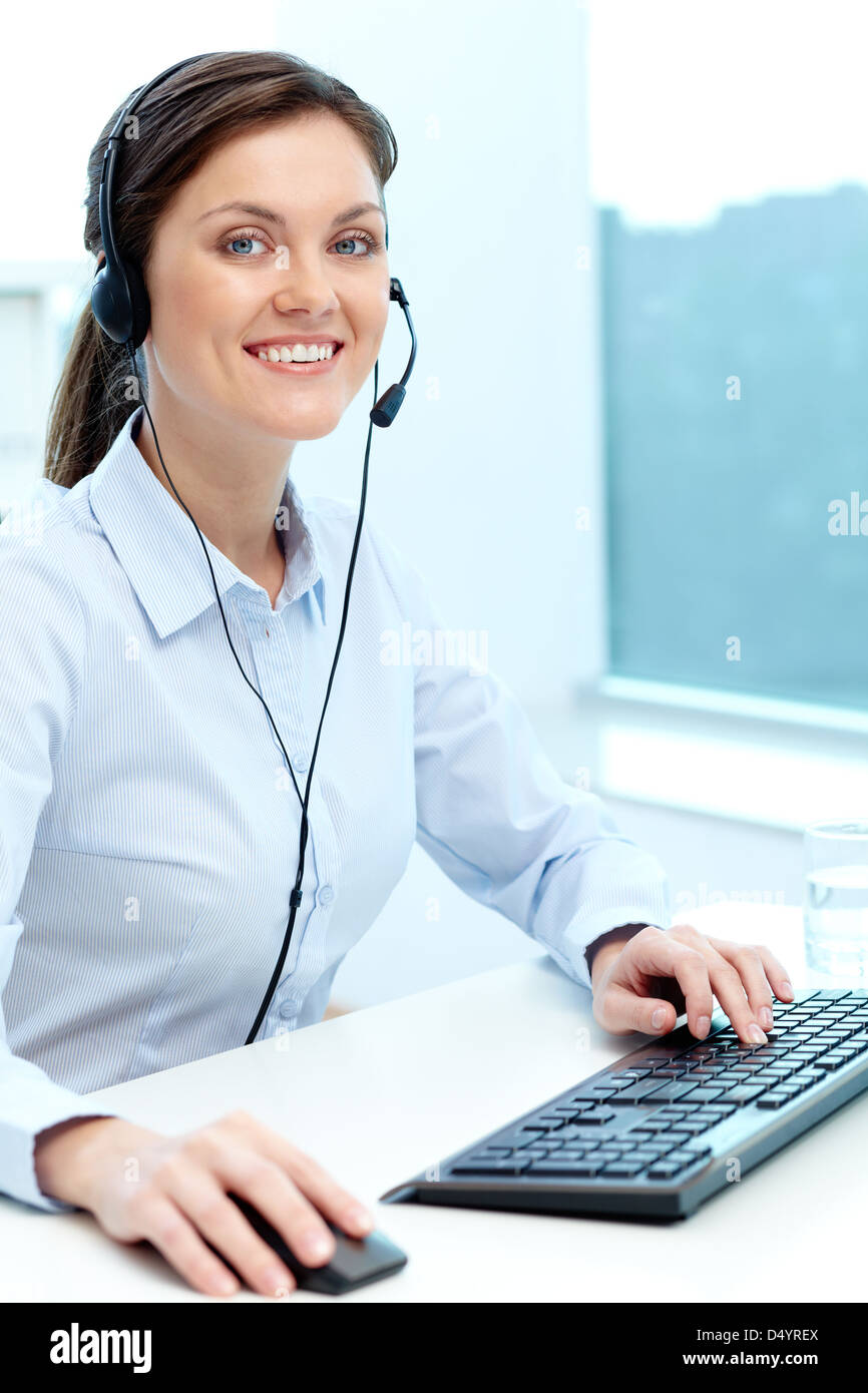 Portrait of young operator with headset looking at camera with friendly ...