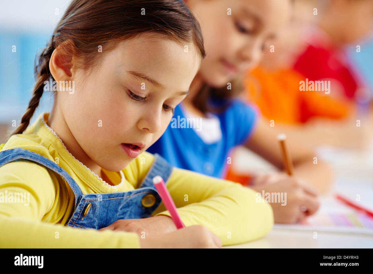 Portrait of lovely girl drawing at workplace with schoolmate on ...
