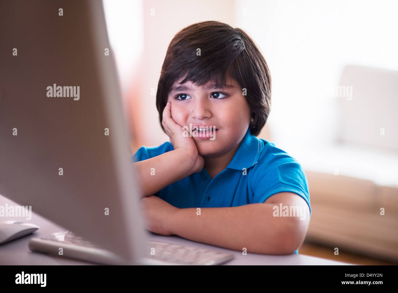 Boy using a desktop computer and thinking Stock Photo - Alamy