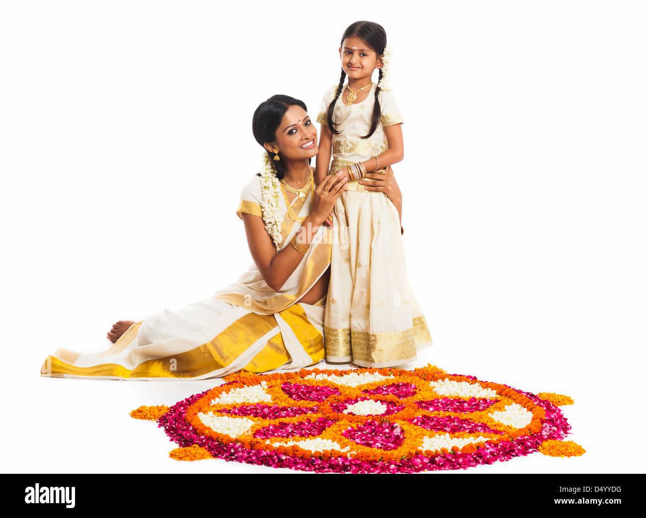 South Indian woman making a rangoli of flowers with her daughter at ...