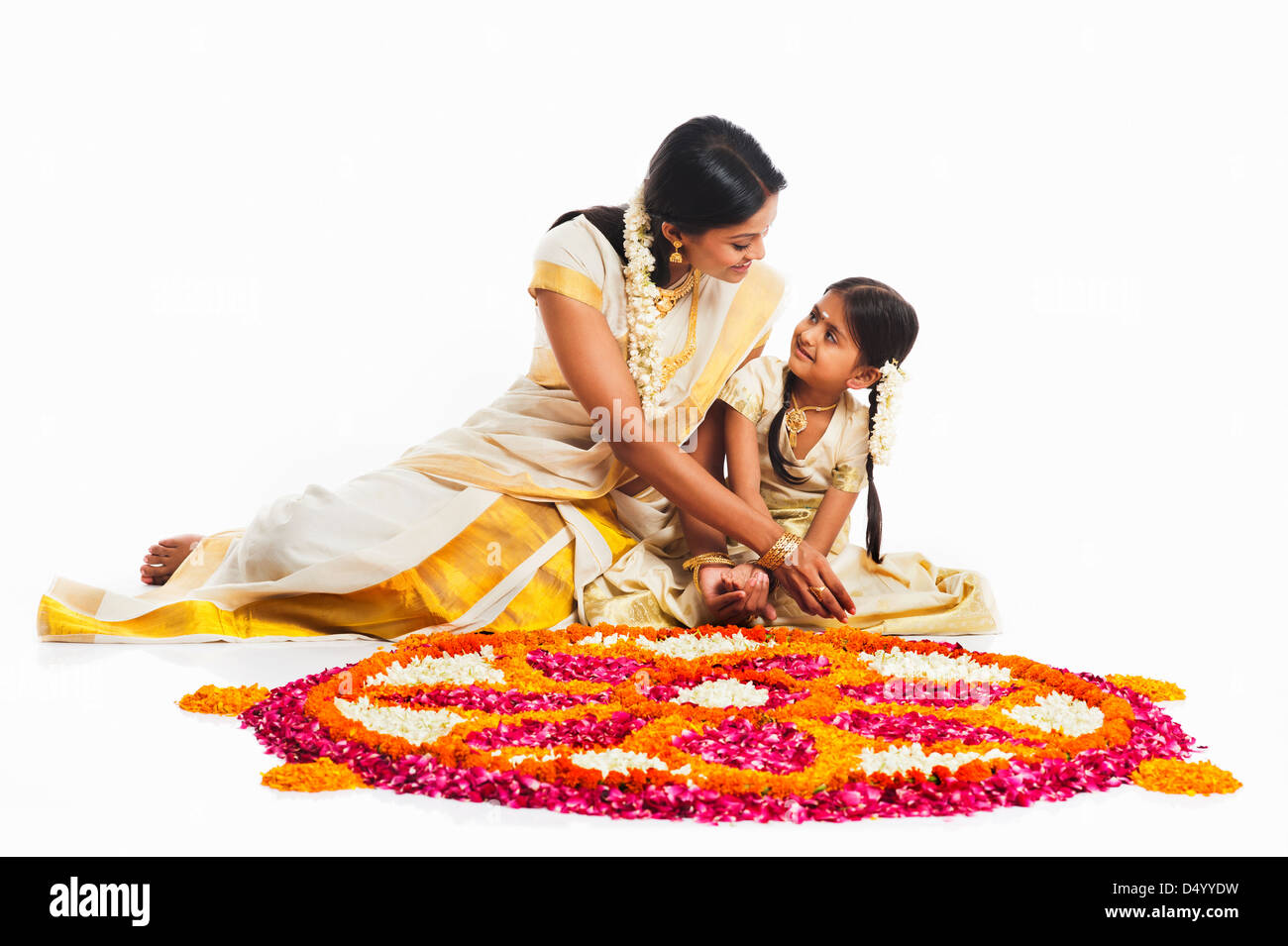 South Indian woman making a rangoli of flowers with her daughter at ...