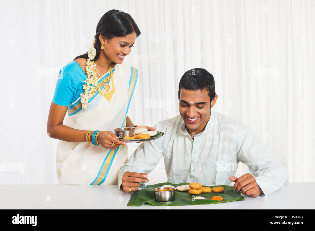 South Indian woman serving food to her husband Stock Photo - Alamy