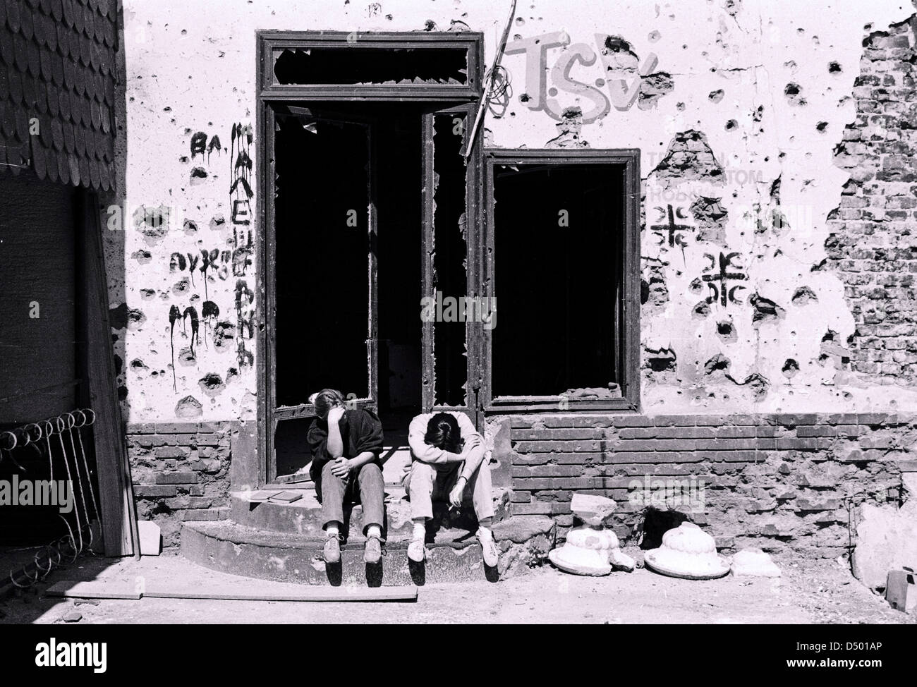 Two girls bow their heads while crying outside a ruined storefront in ...