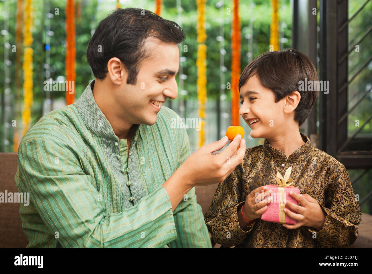 Man feeding laddoo to his son on Diwali Stock Photo - Alamy