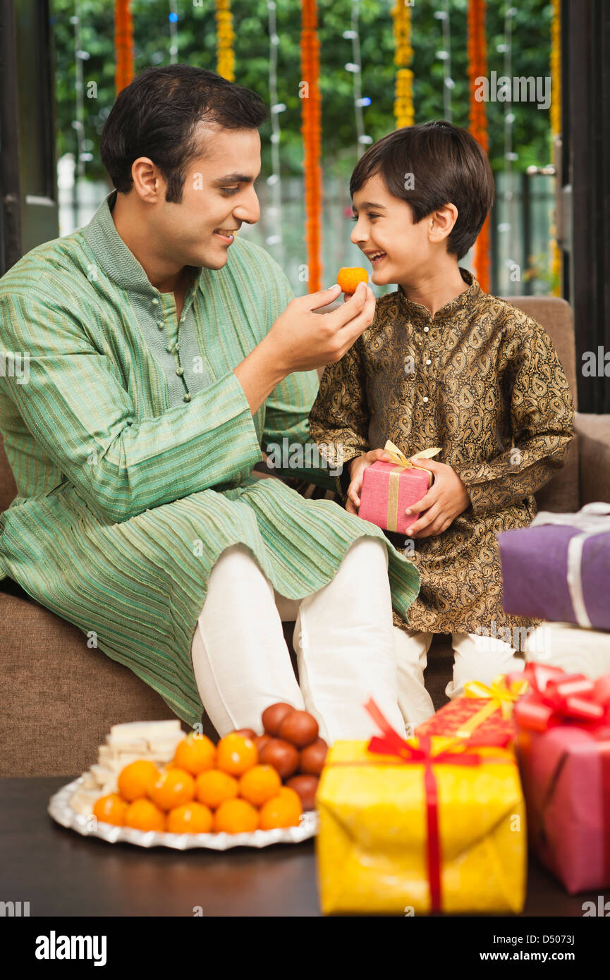 Man feeding laddoo to his son on Diwali Stock Photo - Alamy