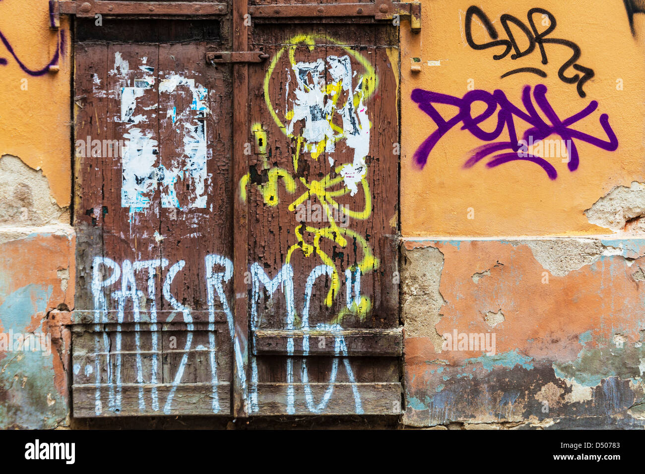 Old shuttered window and graffiti on a crumbling plaster wall in a side ...