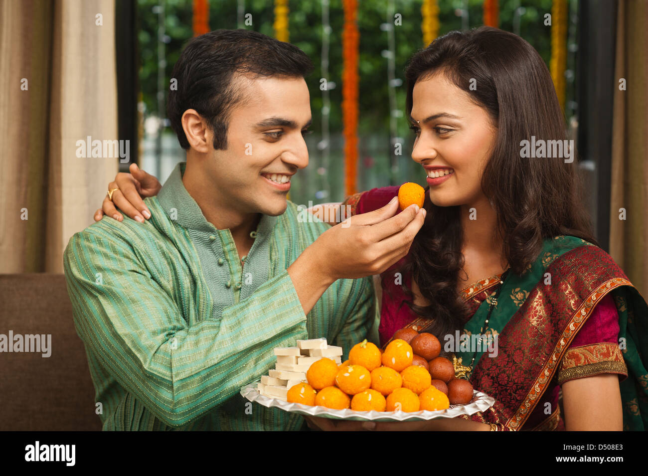 Man feeding laddoo to his wife on Diwali Stock Photo - Alamy
