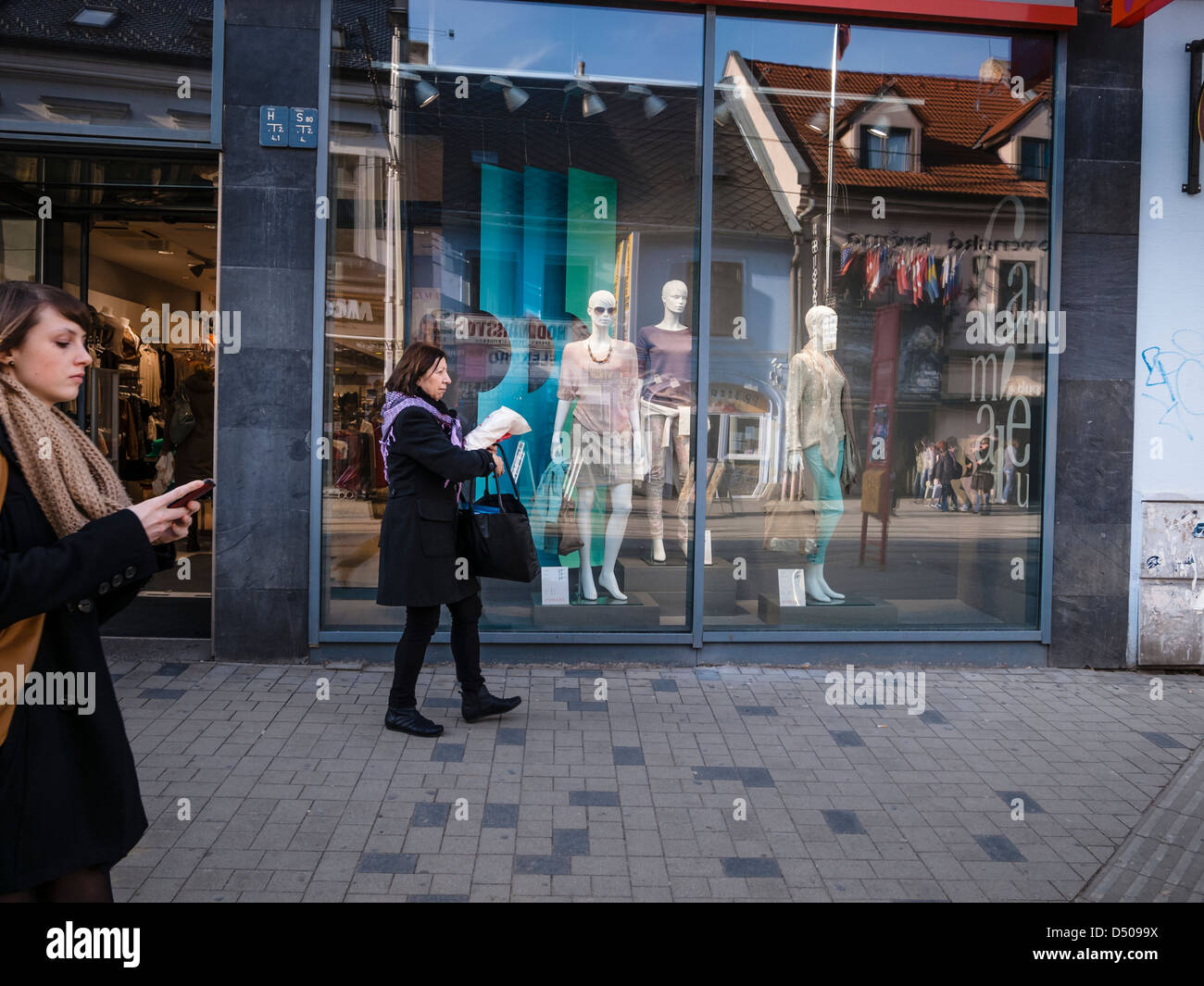 two women on Obchodna street walking around a shop screen with ...