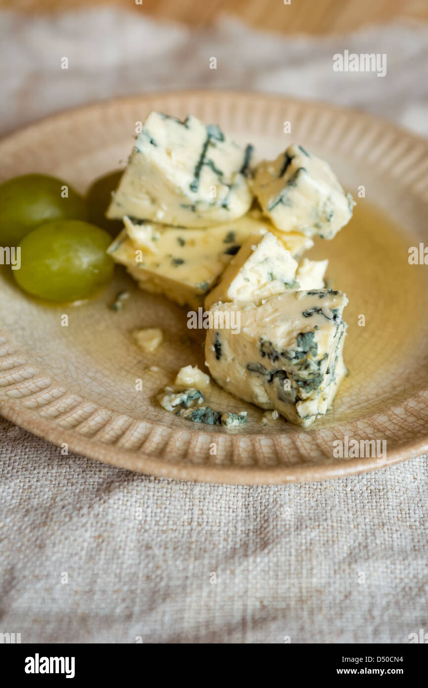 Close-up of blue mold cheese and grapes on a plate. Wooden background ...