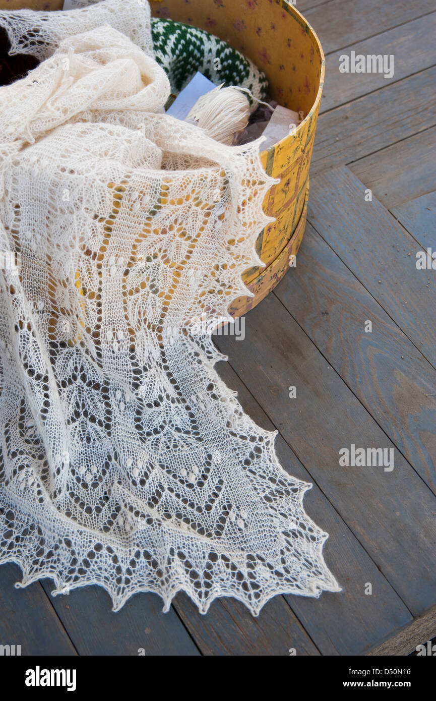 A knitted lacy blanket cascades out of an antique hat box, where other ...