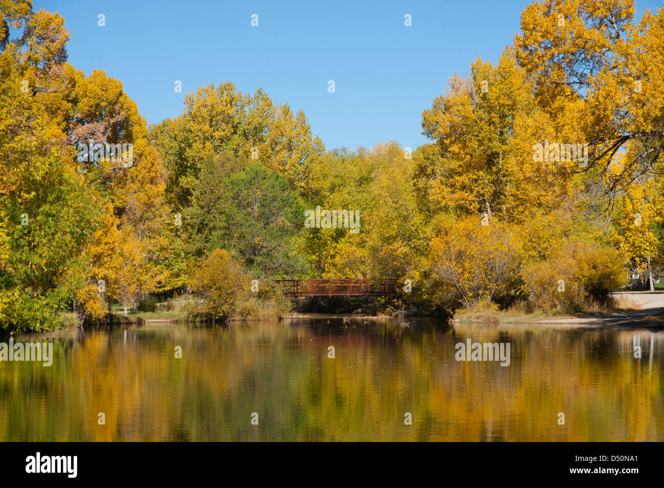 A small lake, complete with footbridge, reflects the harvest colors of ...