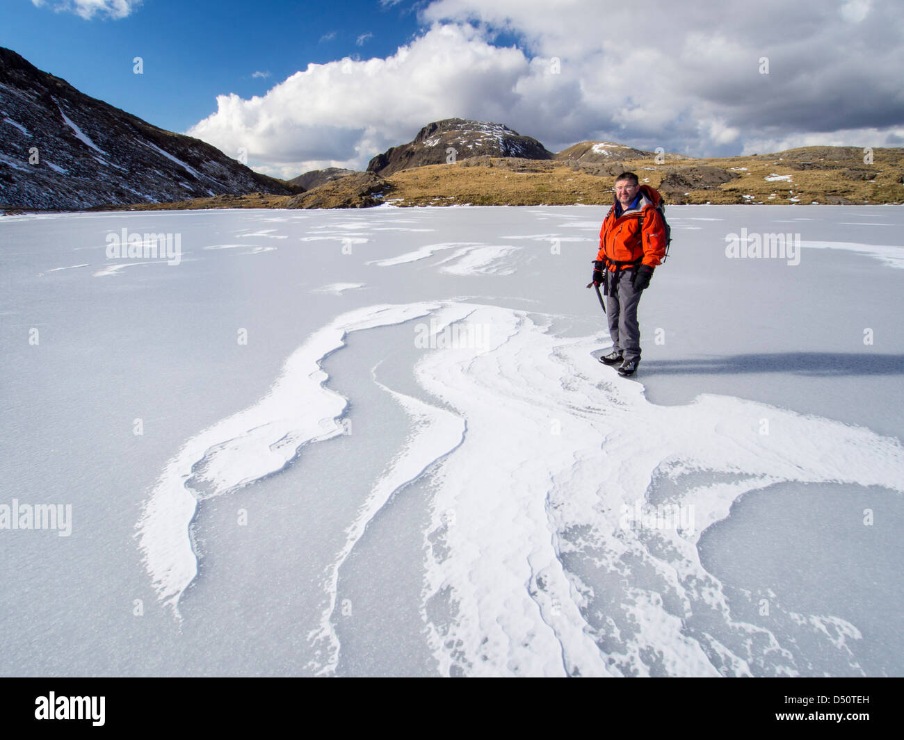 A climber on a frozen Sprinkling tarn at the head of Borrowdale in the ...