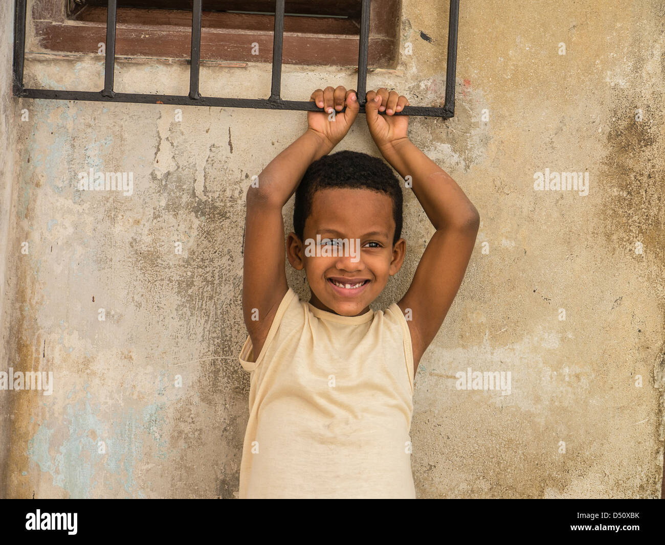An 8-10 year old Hispanic Cuban boy holds on to an iron window grate ...