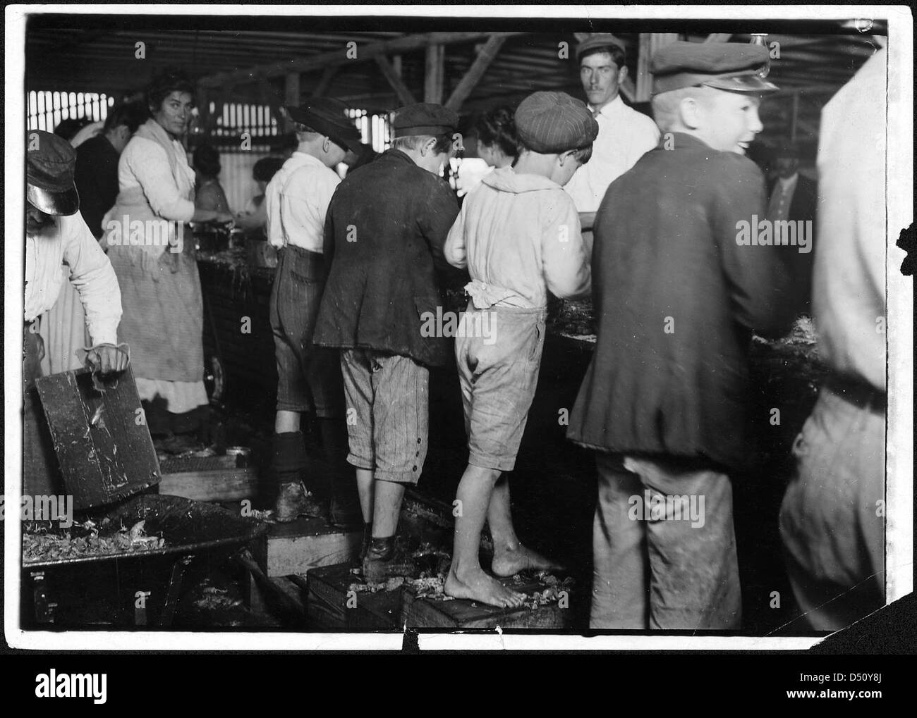 A 1912 photograph by Lewis Hine showing workers, including children ...