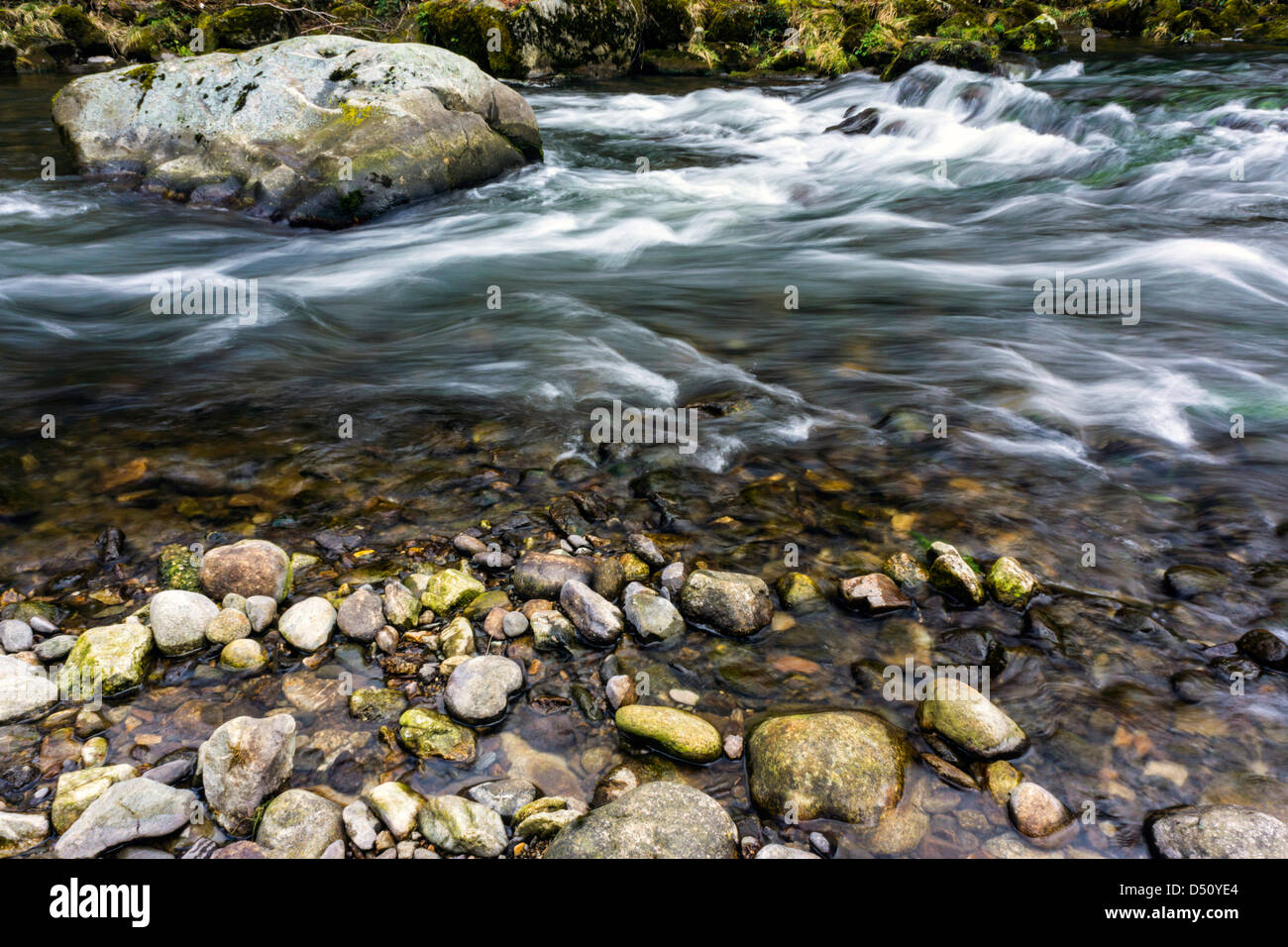 Flowing river with rounded stones on the beach Stock Photo - Alamy