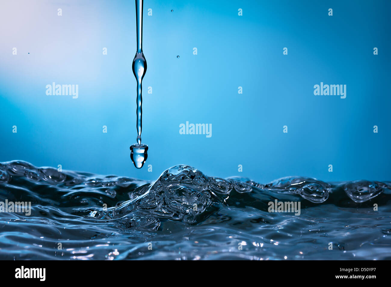 Falling drop on blue background Stock Photo - Alamy