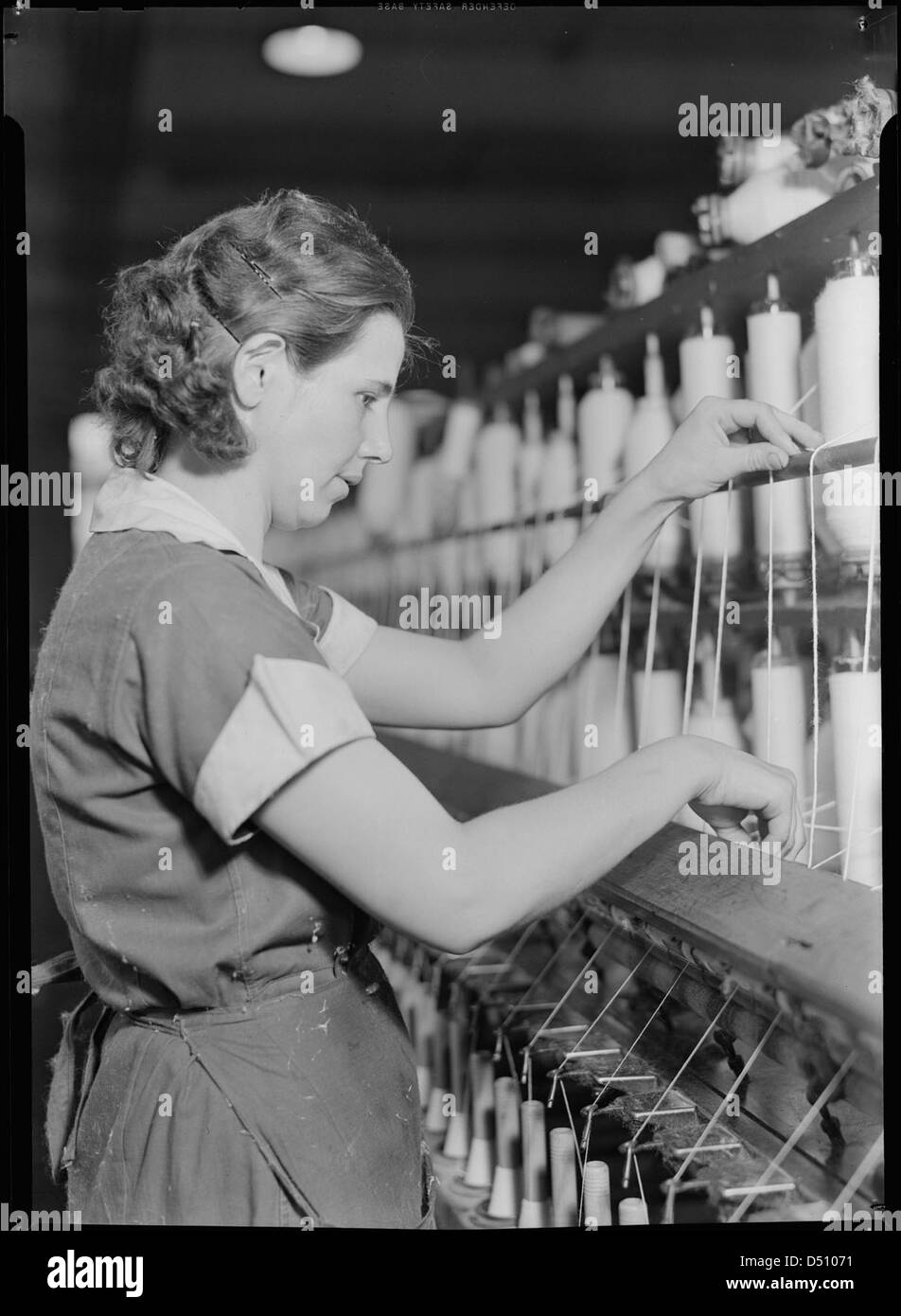 This 1937 photograph by Lewis Hine shows a spinner at work in a textile ...