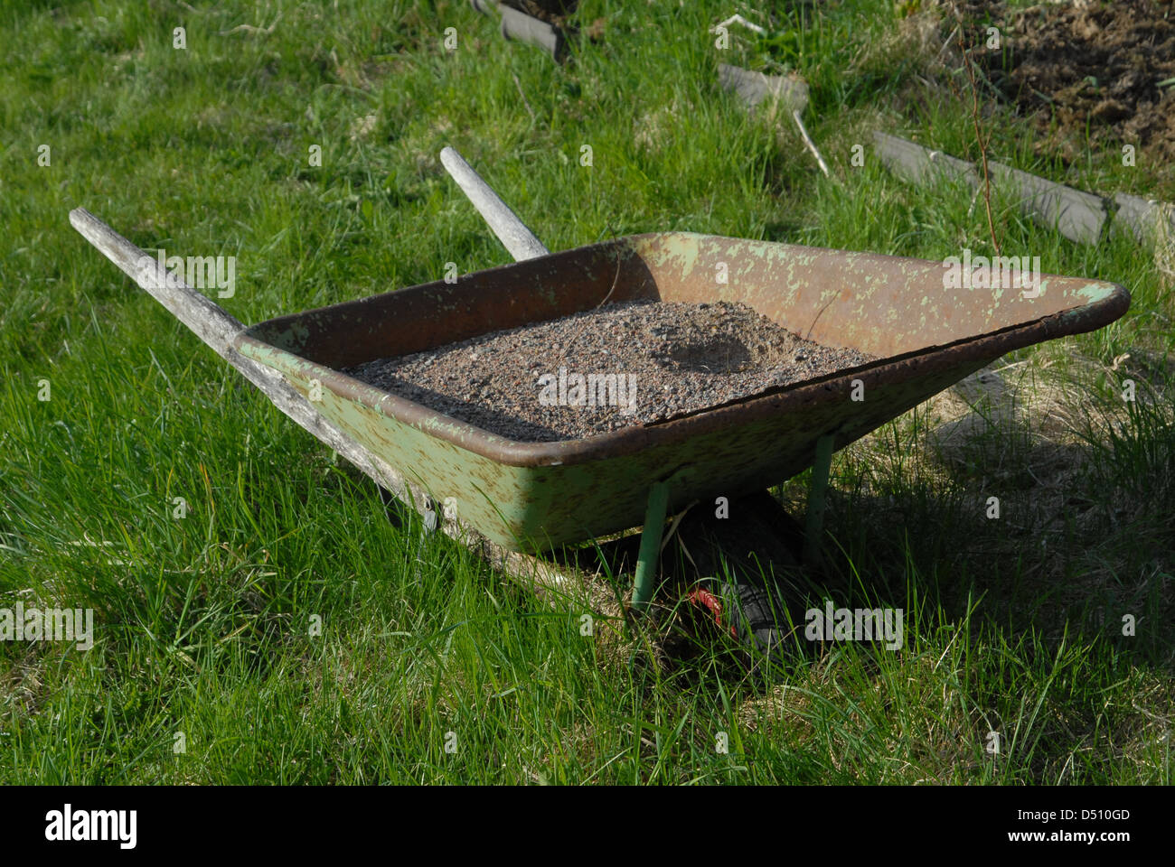 Rusty wheelbarrow filled with gravel Stock Photo - Alamy