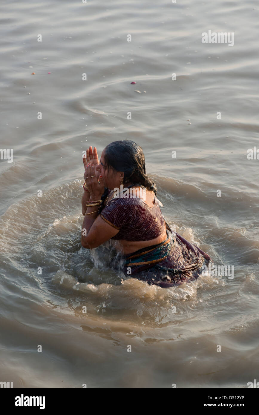 A Hindu devotee engages in ritual bathing in the Sacred Yamuna river at ...