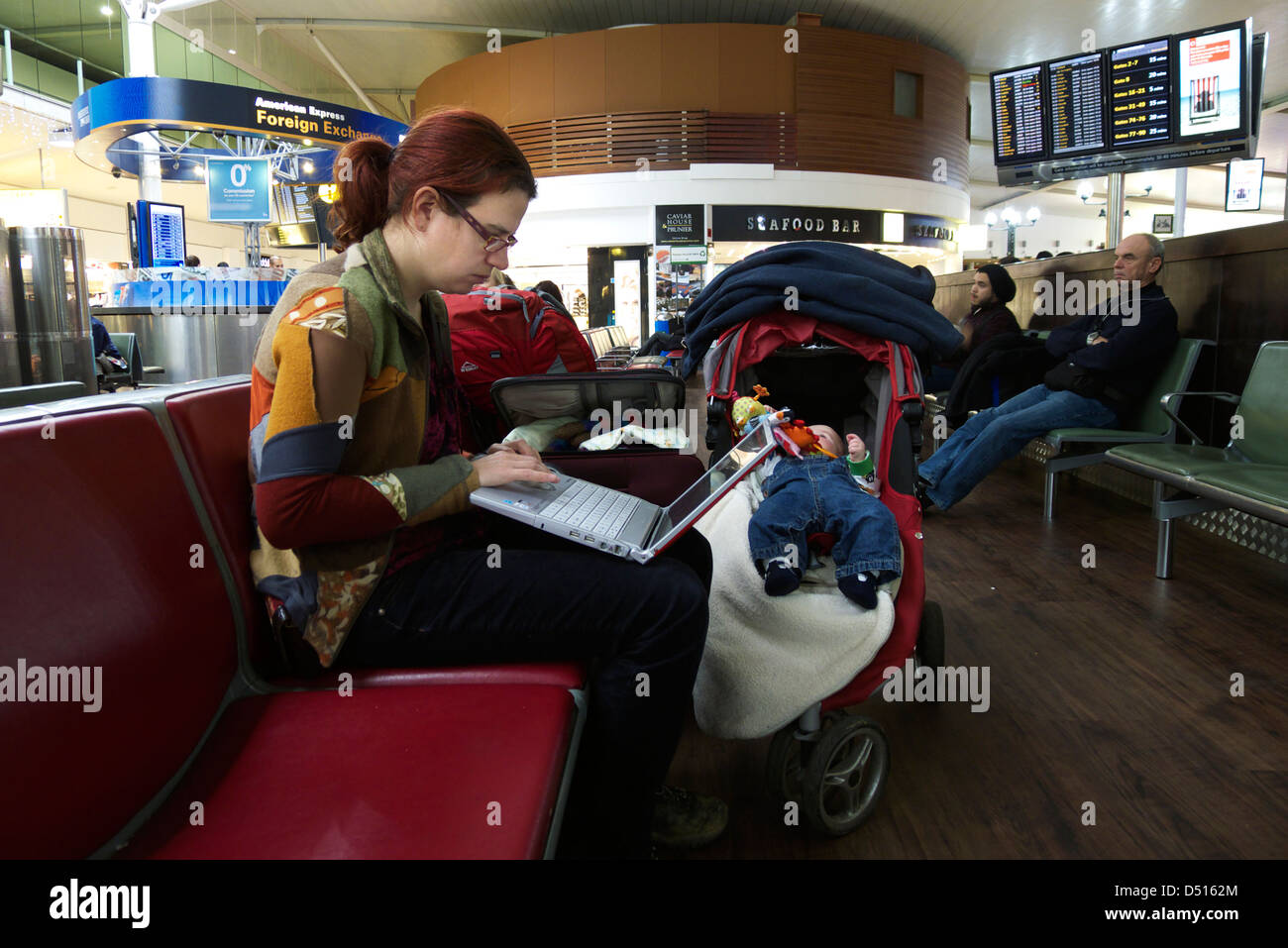 A woman using a laptop computer in an airport departure lounge Stock ...