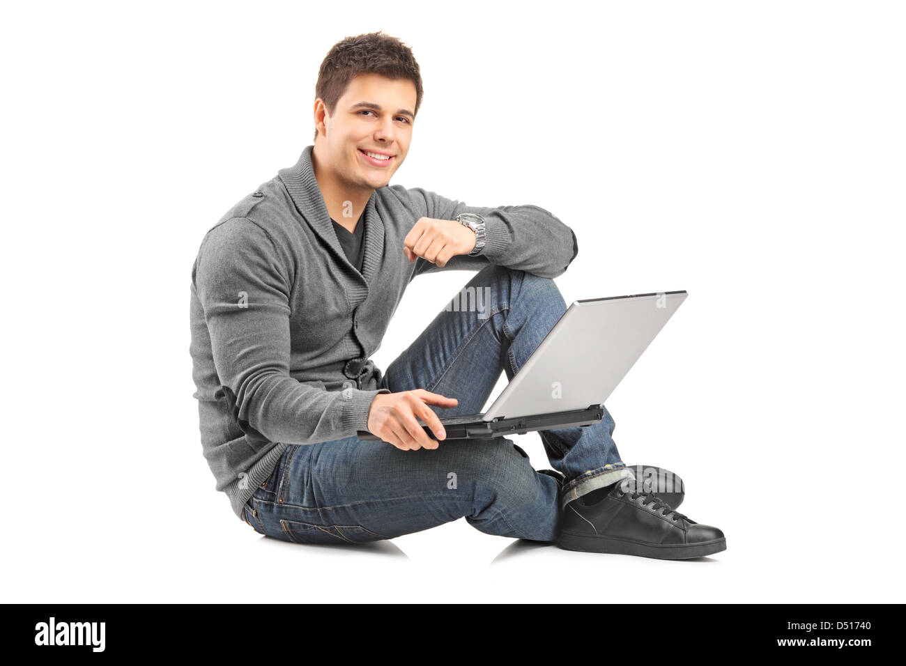 Handsome guy working on a laptop and sitting on a floor, isolated ...
