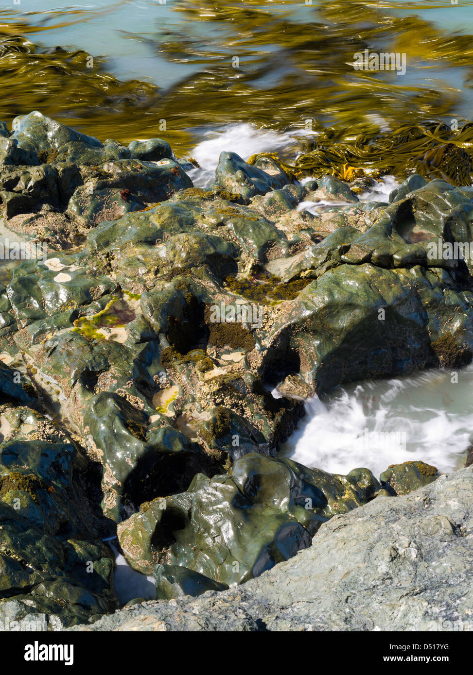 Waves crash on sea-side rocks, slowly carving the rock and creating ...