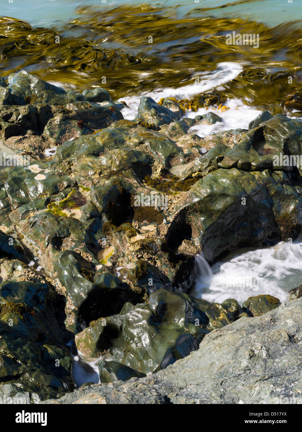 Waves crash on sea-side rocks, slowly carving the rock and creating ...